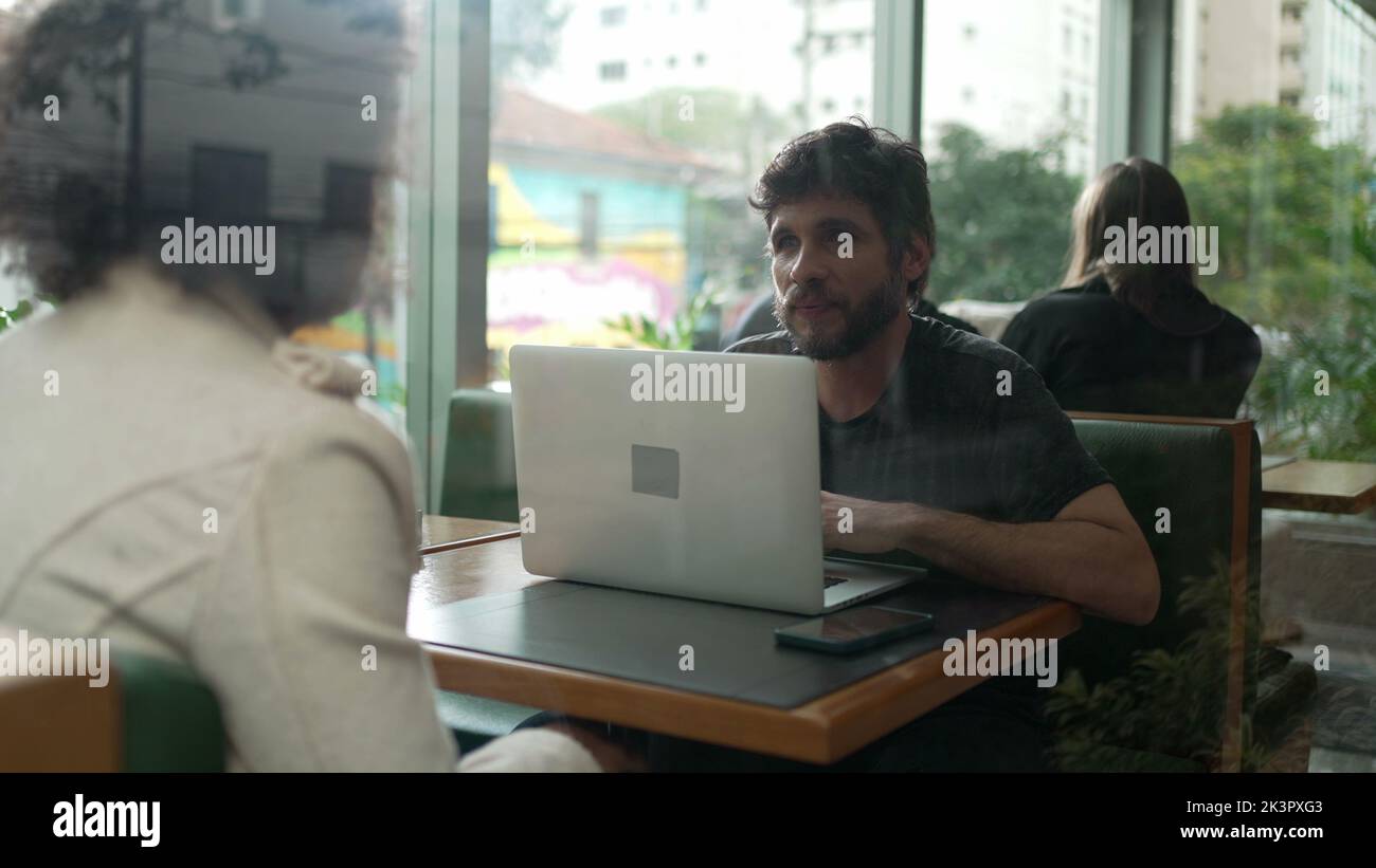 People inside coffee shop through glass window. Men and women customers ...