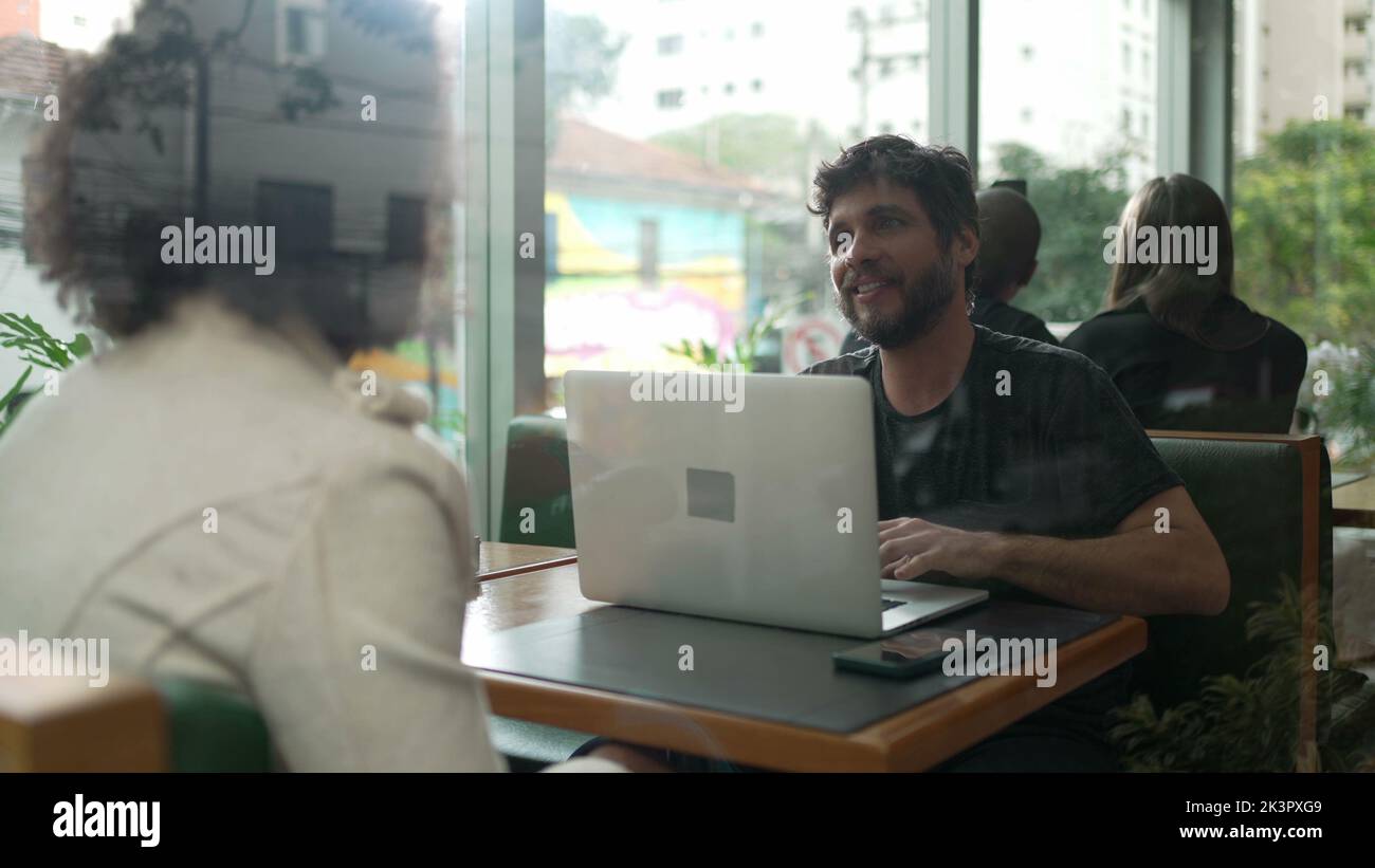 People inside coffee shop through glass window. Men and women customers talking inside cafe ...