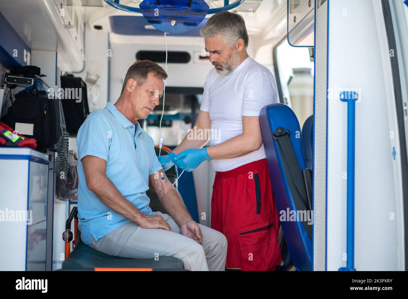 Ambulance doctor preparing the patient for an intravenous infusion ...