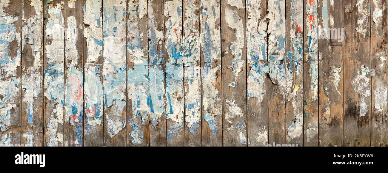 Weathered remains of old vintage advertising posters on a wooden wall ...