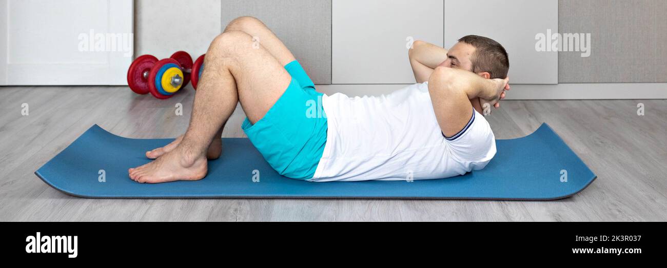 A strong, healthy man with muscles, training at home in the plank ...