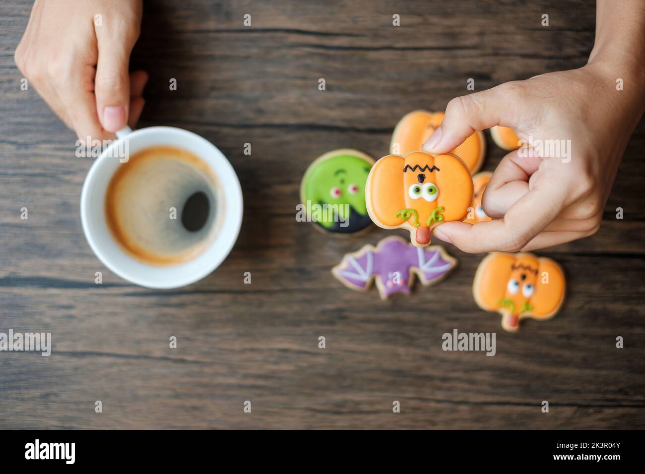 hand holding coffee cup during eating funny Halloween Cookies. Happy ...