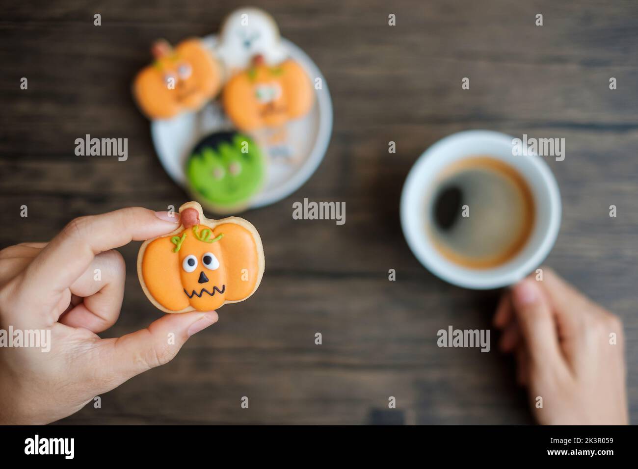 hand holding coffee cup during eating funny Halloween Cookies. Happy ...
