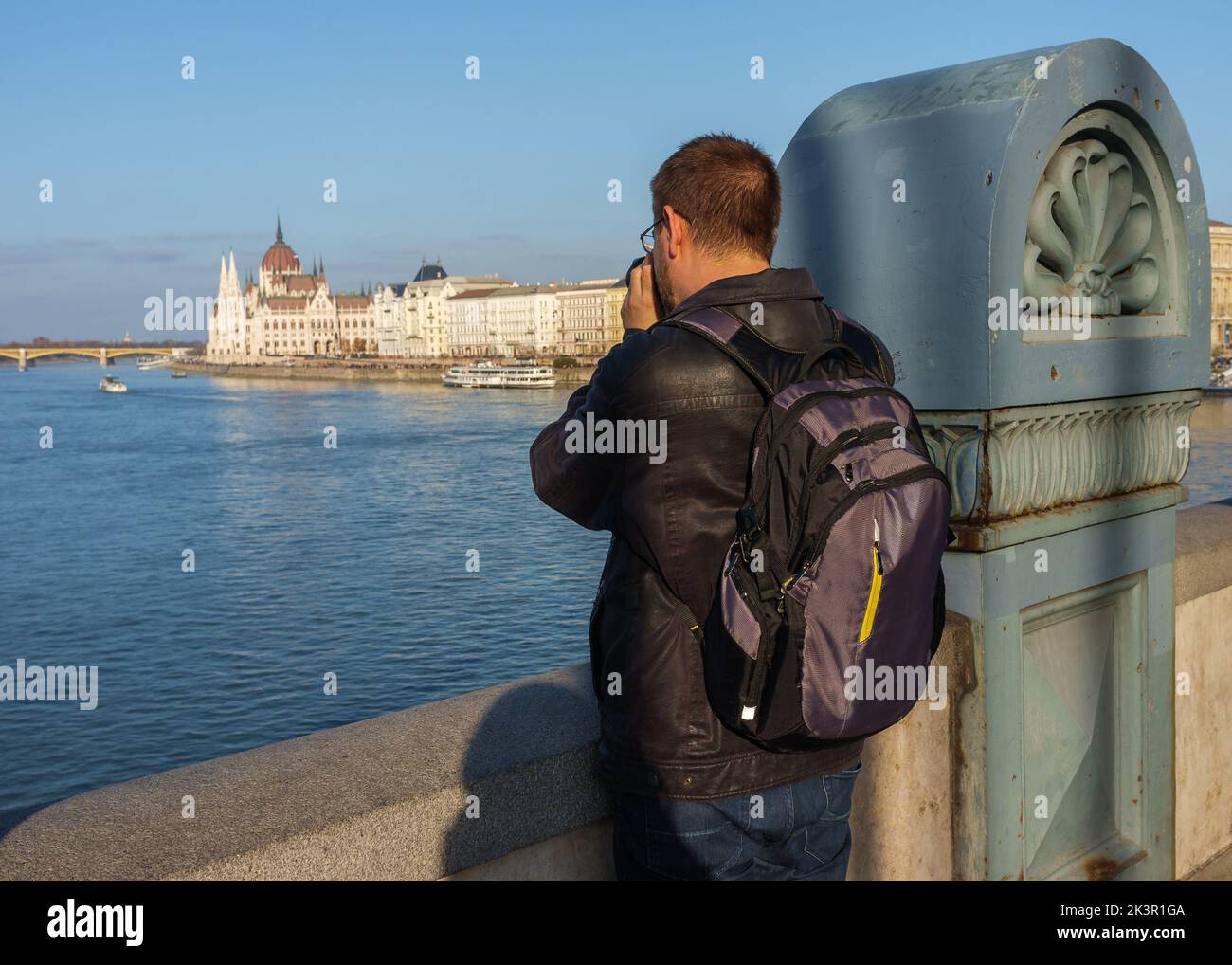 A man with a backpack taking a photo of the Hungarian parliament ...