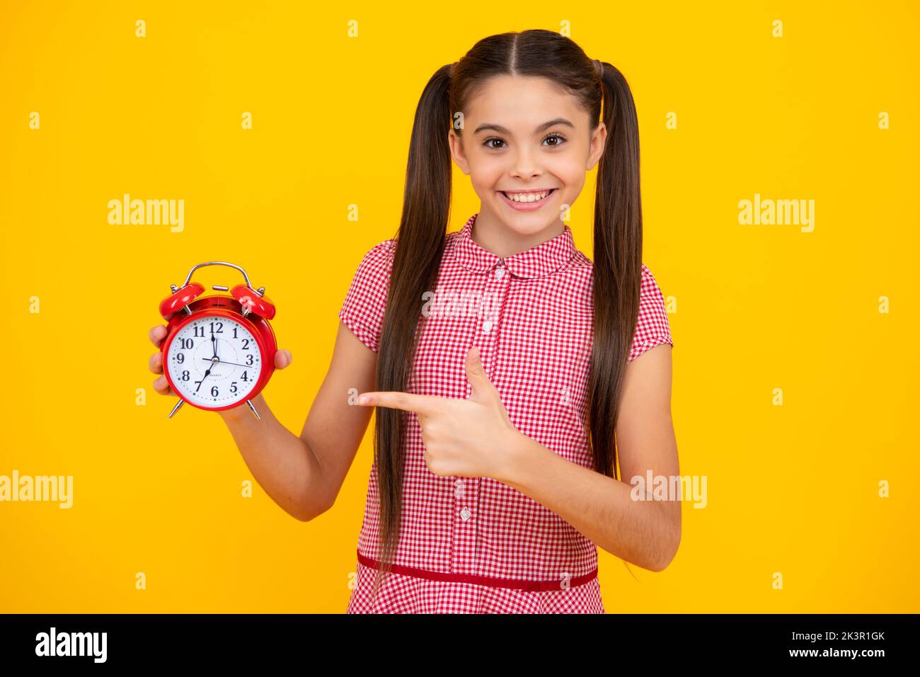 Punctual teen girl checking time. Child with alarm clock showing time ...
