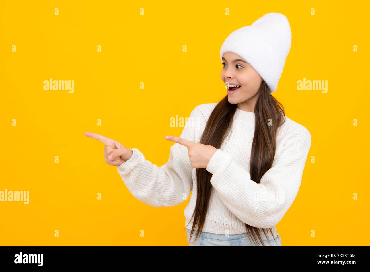 Positive teenager child points aside with cheerful expression, shows ...