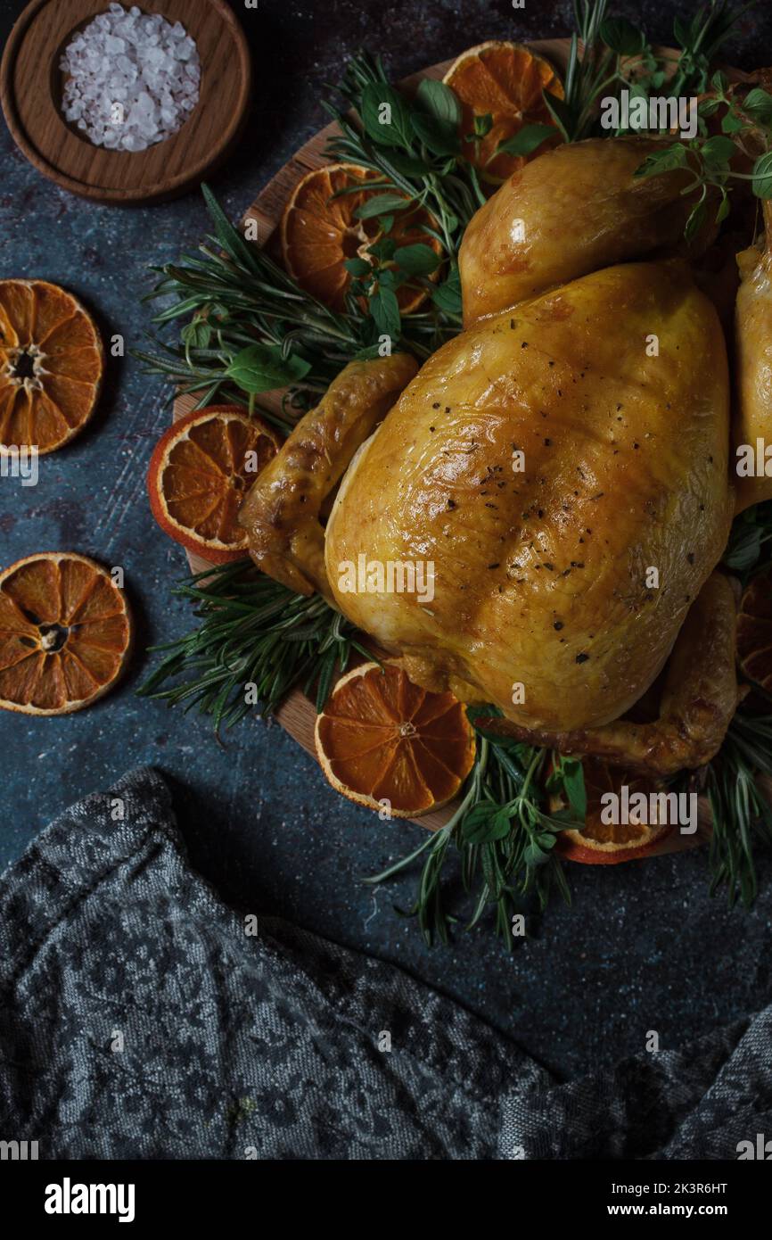 Whole backed chicken on wood plate decorated by dried sliced oranges ...
