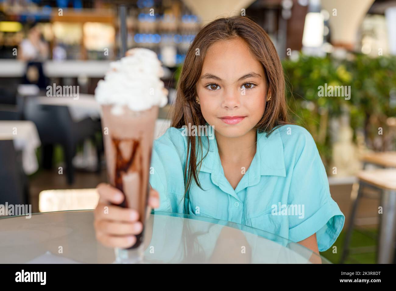 Beautiful child kid girl eating a chocolate shake in a restaurant. Cold ...