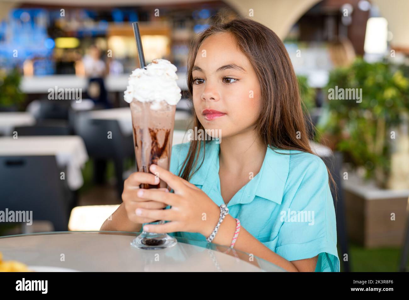 Beautiful child kid girl eating a chocolate shake in a restaurant. Cold ...