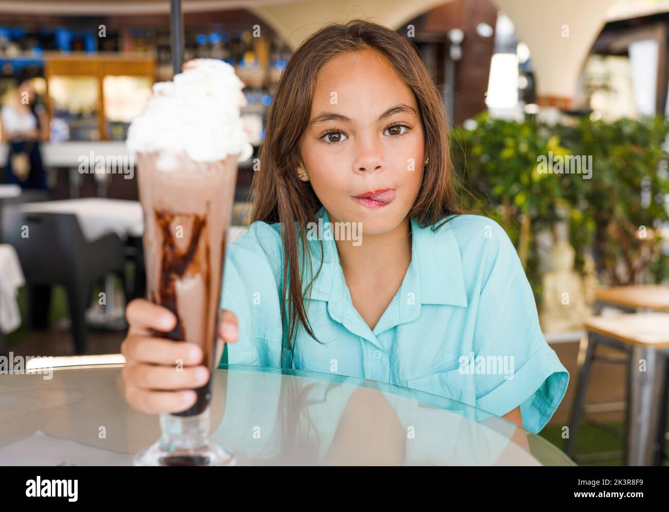 Beautiful child kid girl eating a chocolate shake in a restaurant. Cold ...