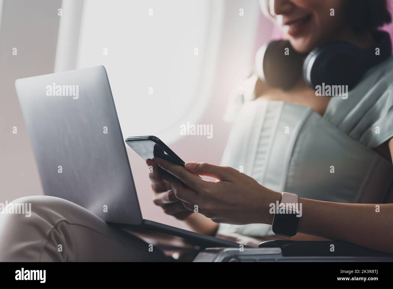 Joyful asian woman sits in the airplane using mobile phone while go to ...