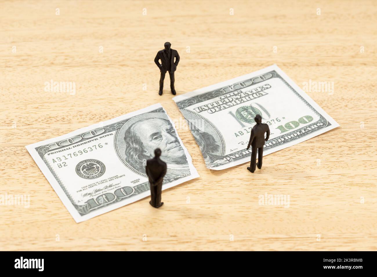 Fake torn dollar banknote and human figurines on wooden table. Rip in ...