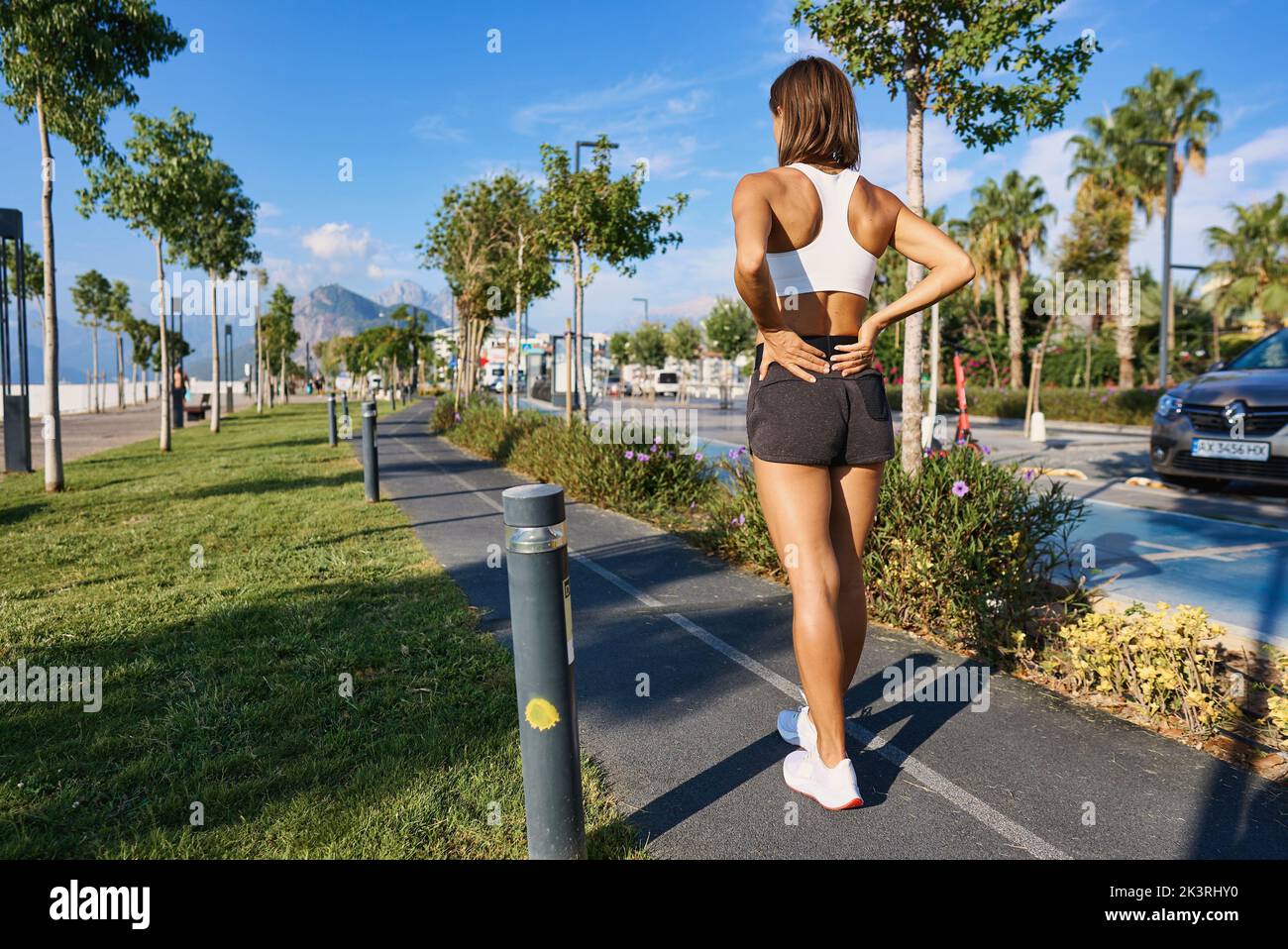 Athletic woman on running track touching hurt back with painful injury ...