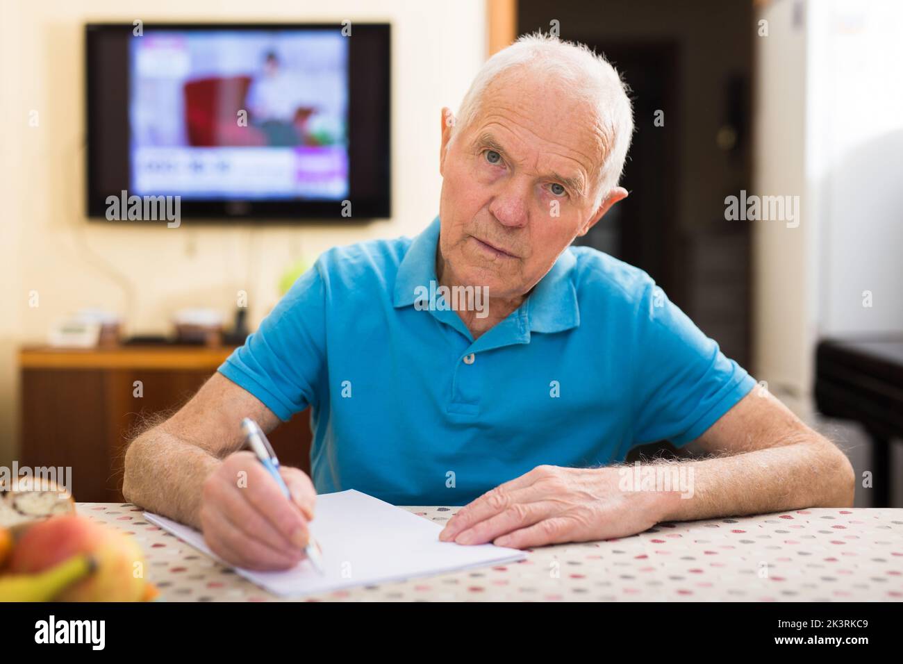 Concentrated elderly man filling up papers at home table Stock Photo ...