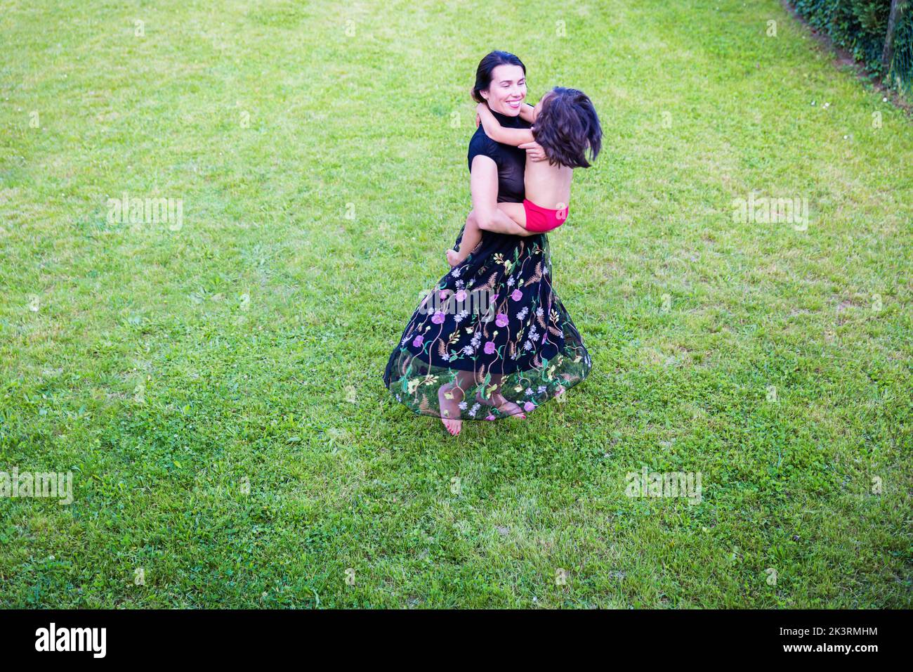 Woman holds her son in her arms and they dance together in the backyard ...