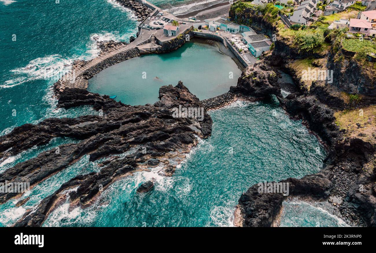 Natural swimming pools and small city on cliff, Atlantic ocean coastline. Madeira island ...