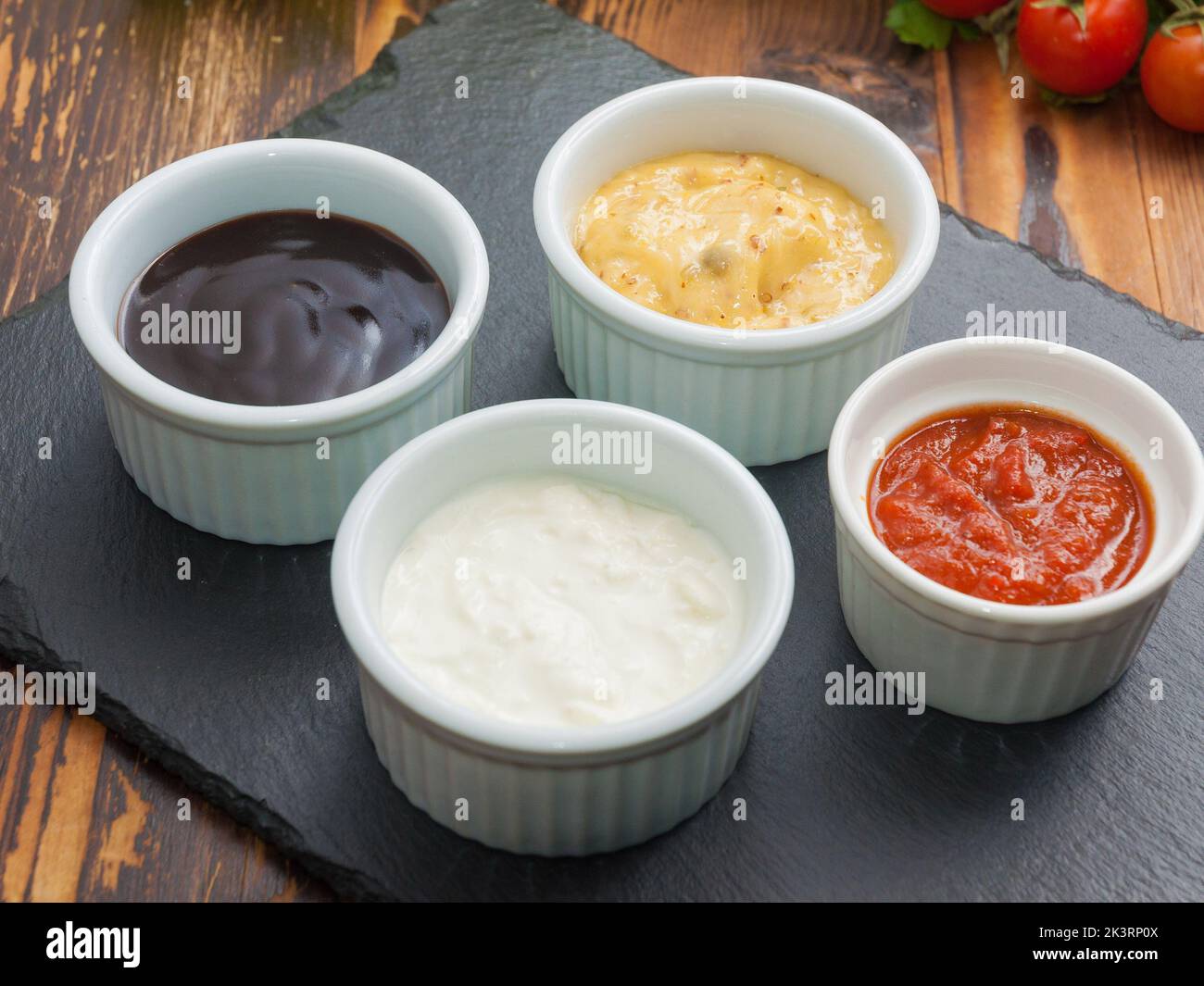 popular sauces: cheese garlic and tomato, in small saucers on a black ...