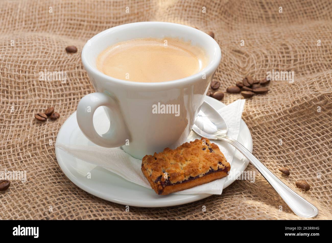 a Cup of tasty coffee with coffee beans on a sackcloth with cookies ...