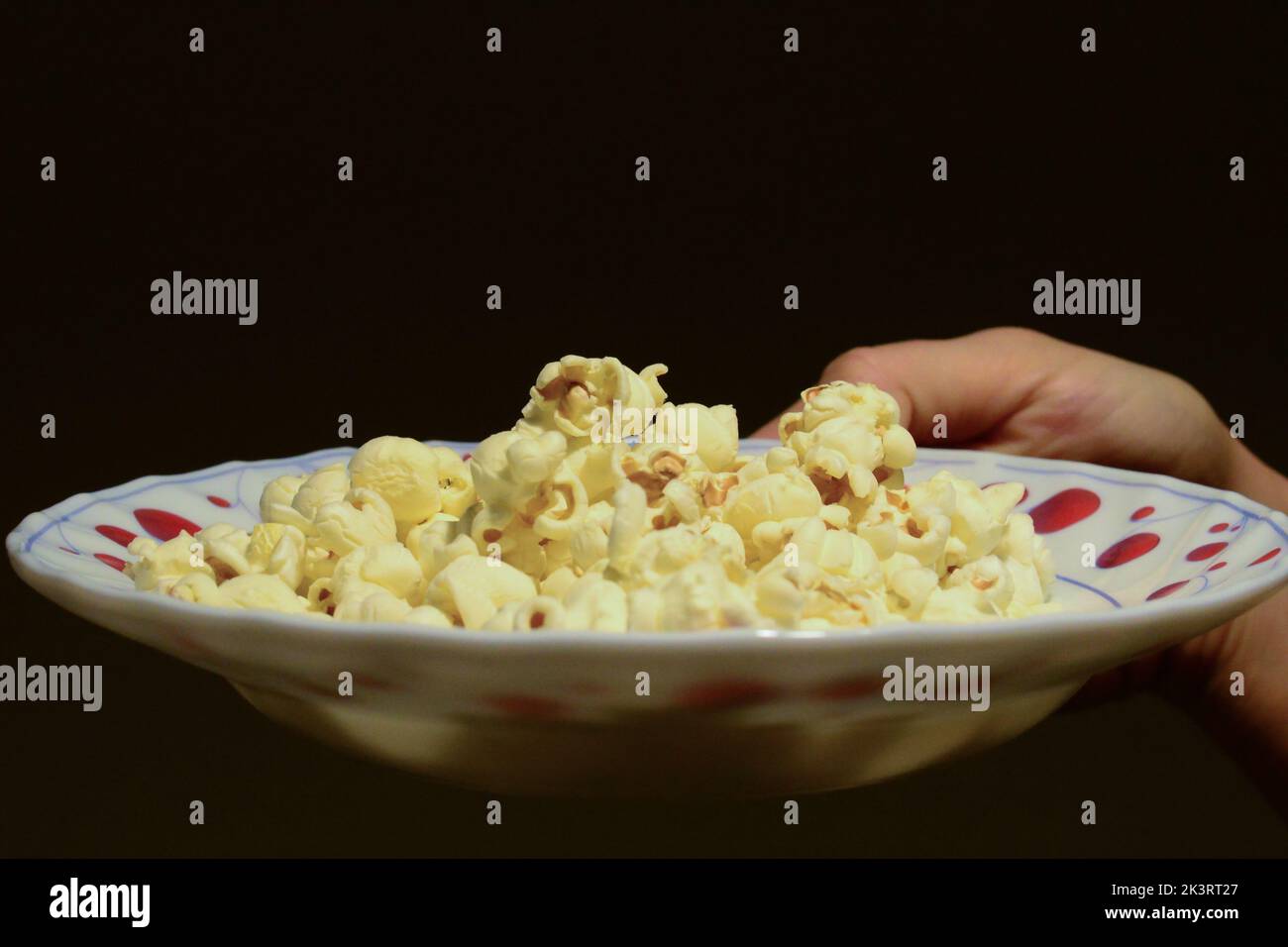 A closeup of human hand holding popcorn on plate Stock Photo - Alamy