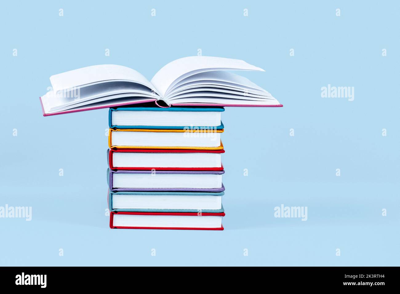 Stack of books on light blue background. Front view, copy space fot ...