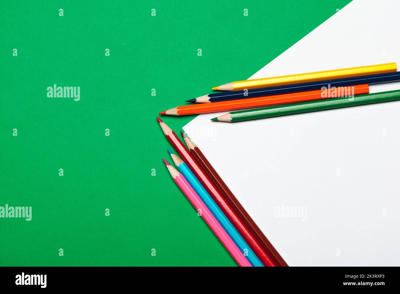 Colorful pencils on a bright green paper background Stock Photo - Alamy