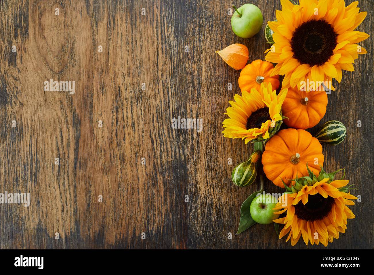 Pumpkin and sunflowers over old wooden background with copy space ...