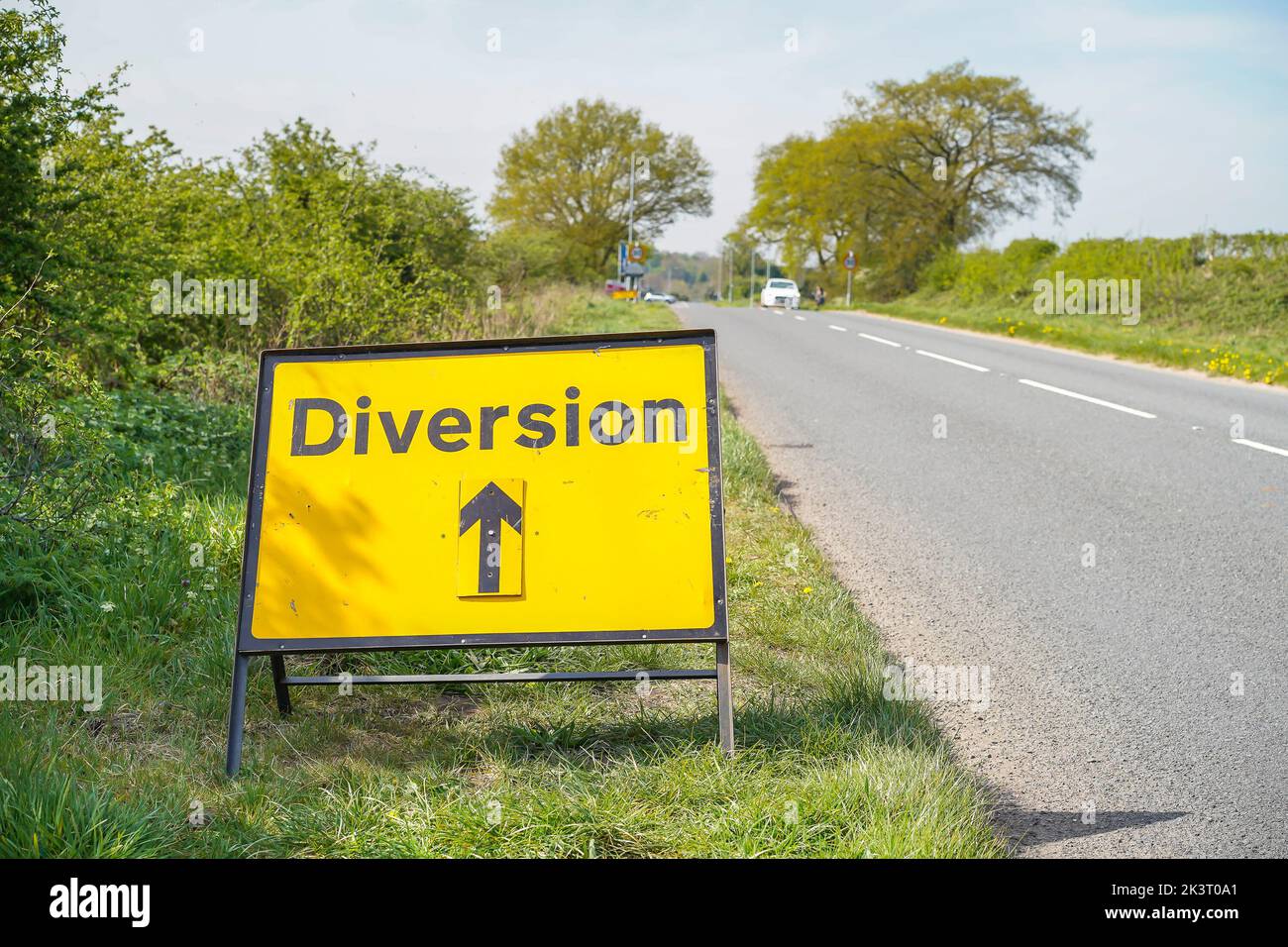 Yellow 'Diversion' road sign in position, isolated by the side of a ...