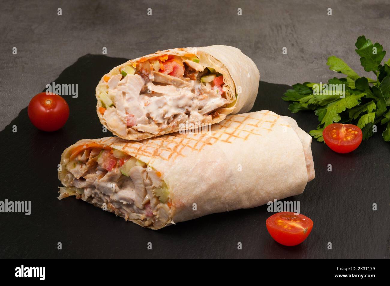 tasty large Shawarma with vegetables and chicken on a dark background ...
