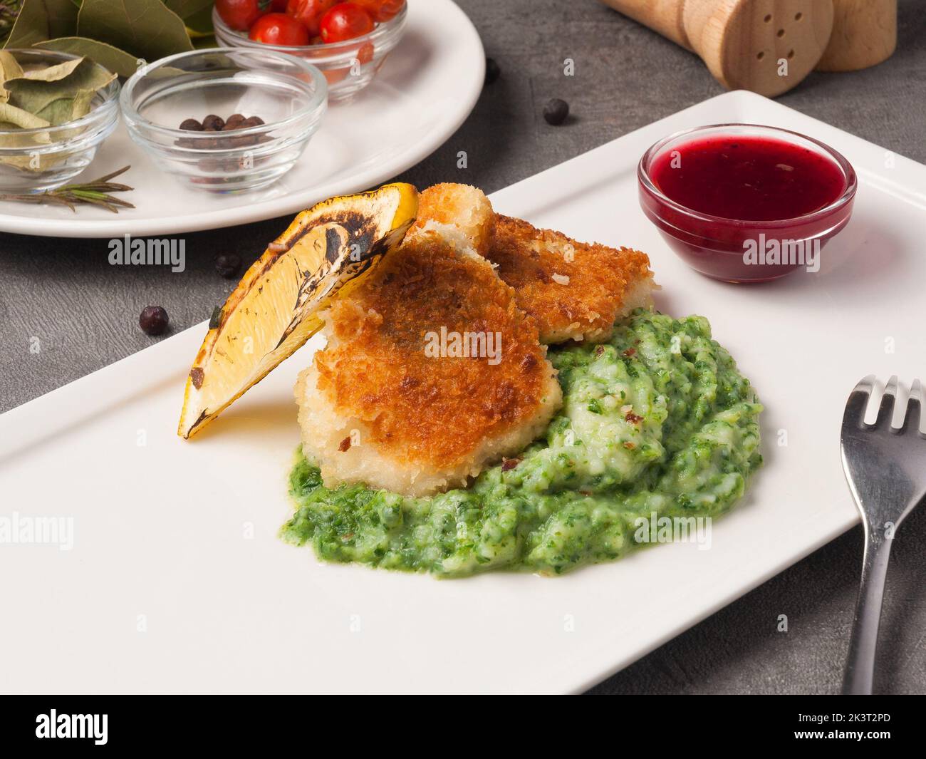 tasty breaded fish fillet with spinach puree garnish Stock Photo - Alamy