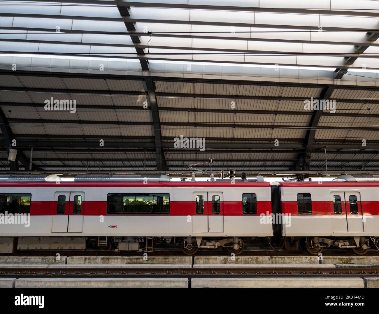 The electric train stops to pick up passengers at a suburban station in ...