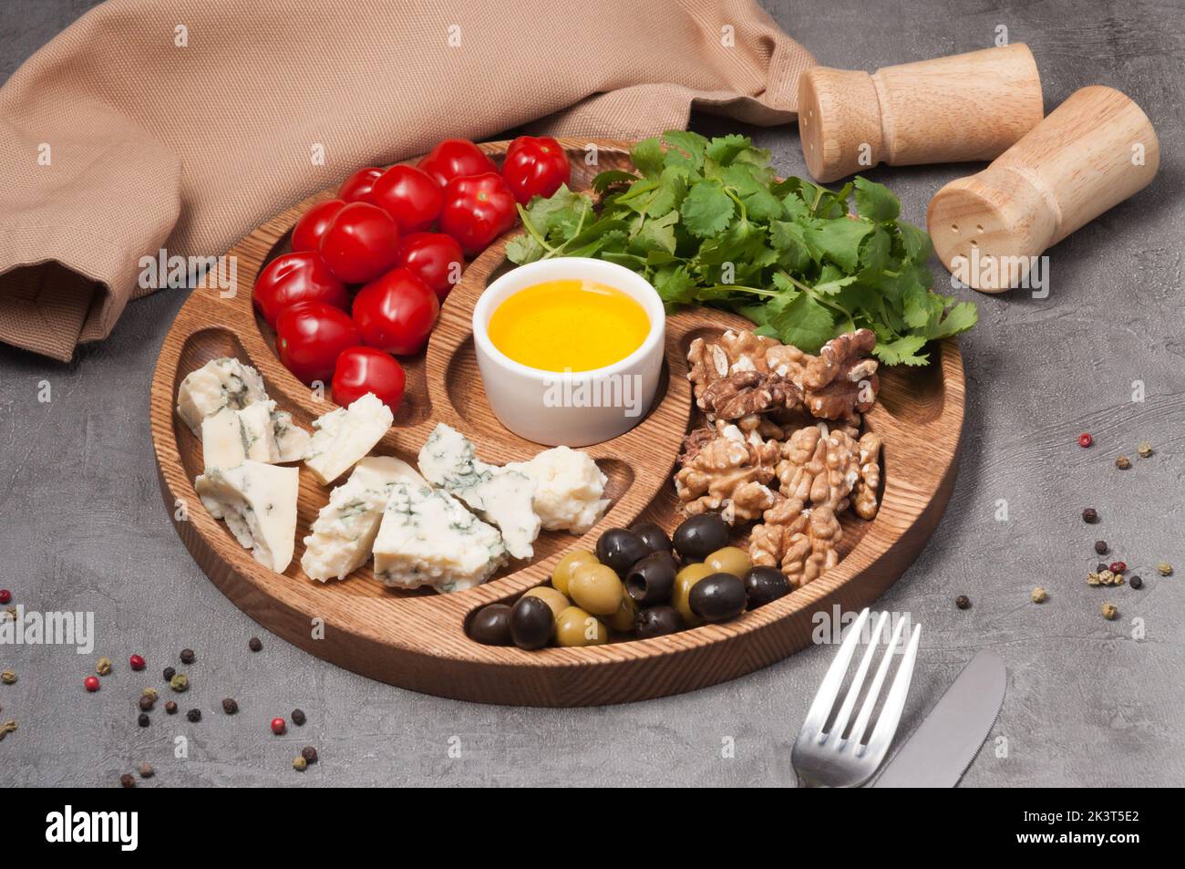 round wooden plate with cheese, nuts, tomatoes and olives Stock Photo ...