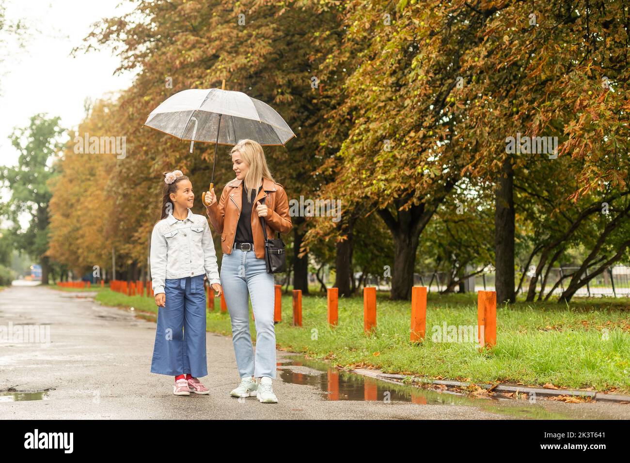 Mom holds a transparent umbrella from which fall autumn leaves ...