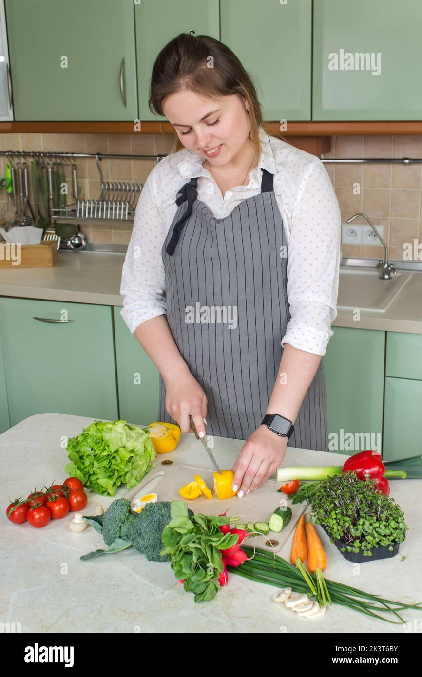 Woman Is Preparing Vegetable Salad In The Kitchen And Cutting