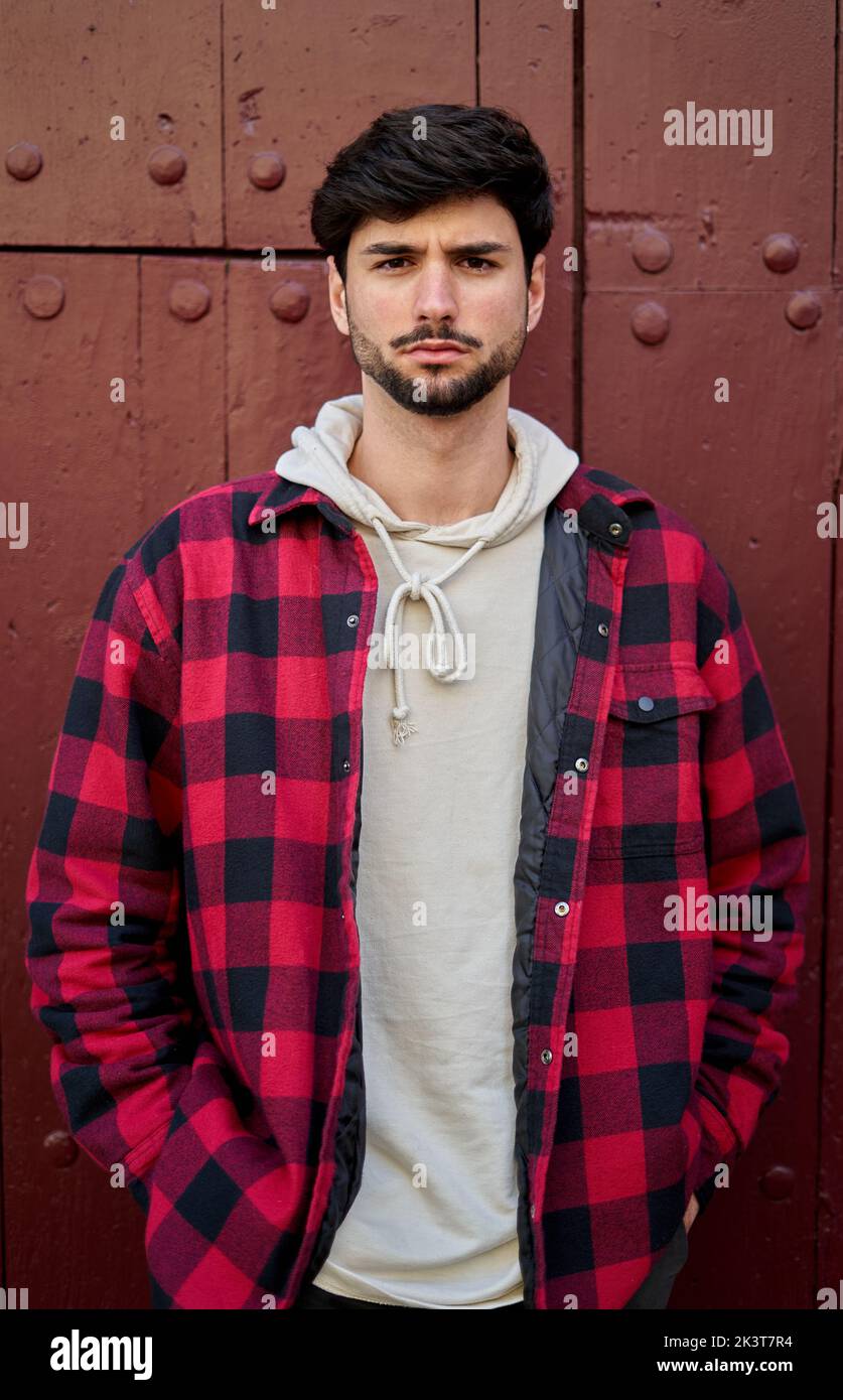 Serene male traveler with beard looking at camera while standing near ...