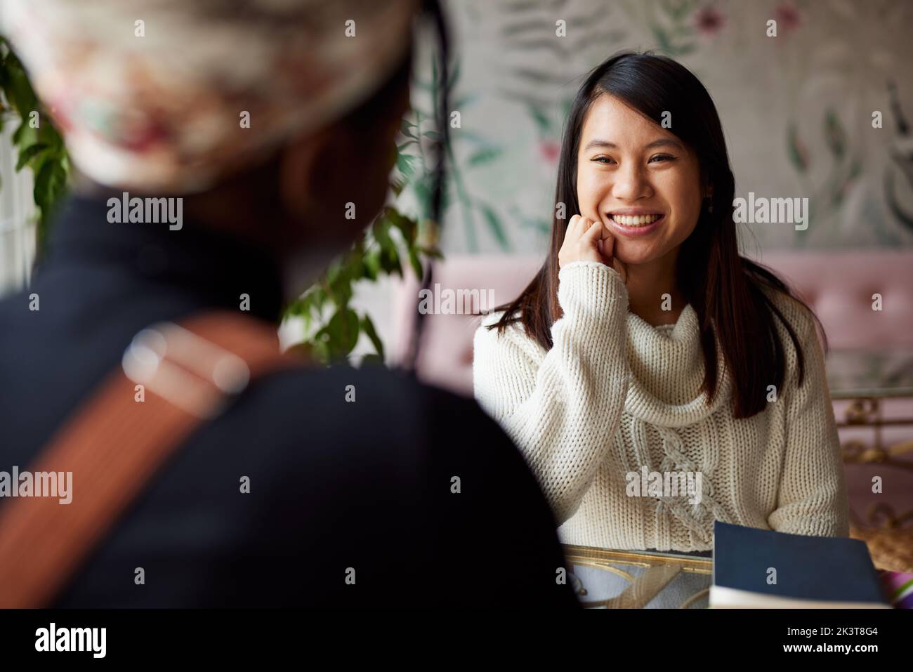Two multicultural female students sitting in cafeteria and study for ...