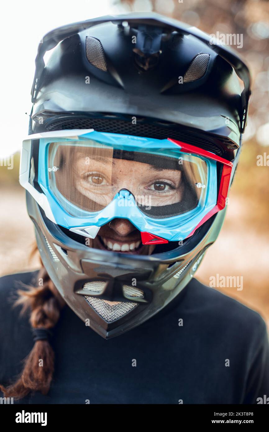 Young woman in safety helmet and sport glasses looking at camera on ...