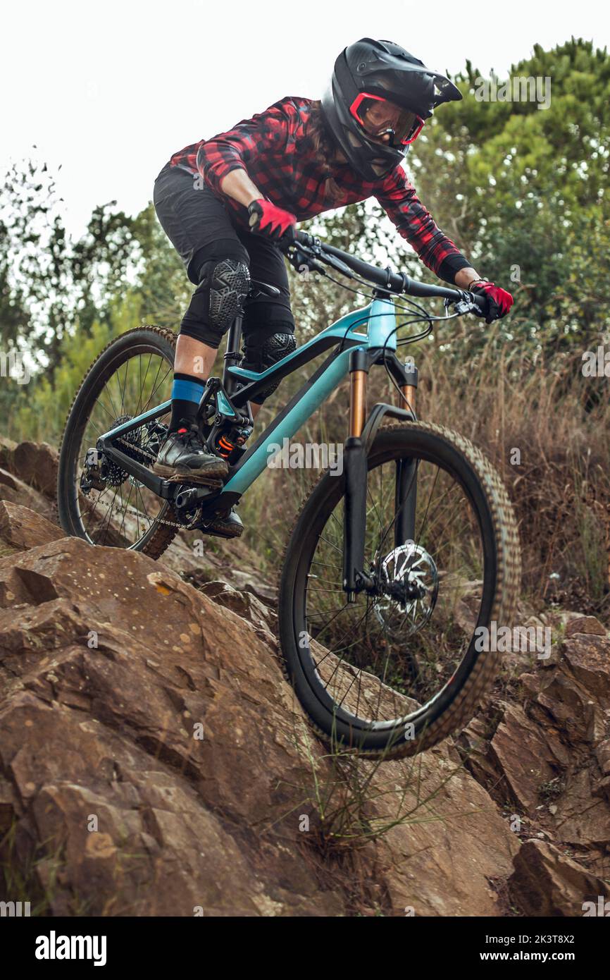 Woman riding on bicycle on path between rocks on hill in forest Stock ...