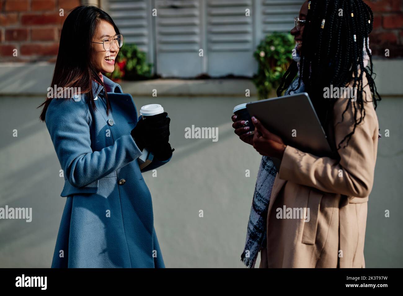 A happy young woman meeting her female friend in cafe garden. Reunion ...