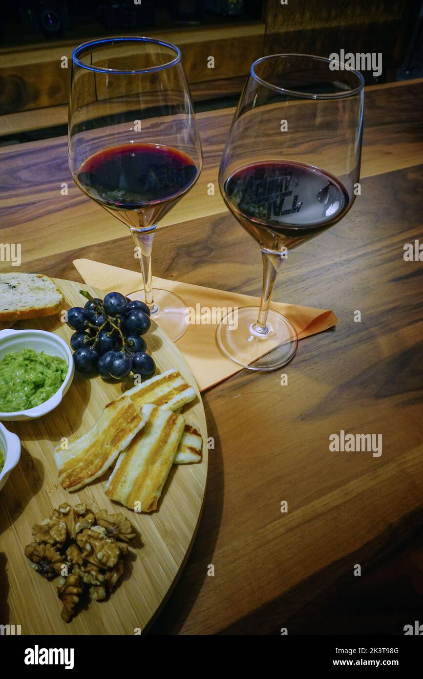 A vertical closeup of two glasses of red wine and appetizers on the ...