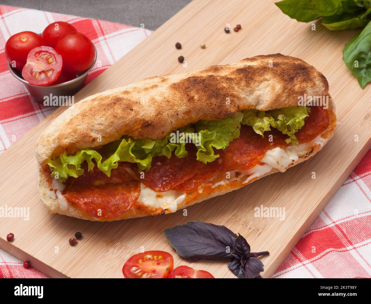 tasty pepperoni panini with cream cheese and salad on a wooden board ...