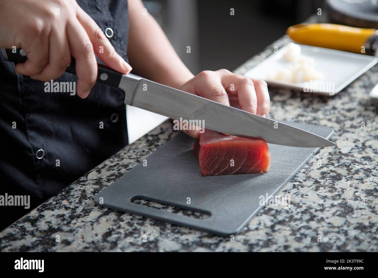 Professional cropped unrecognizable female chef in uniform cutting raw ...