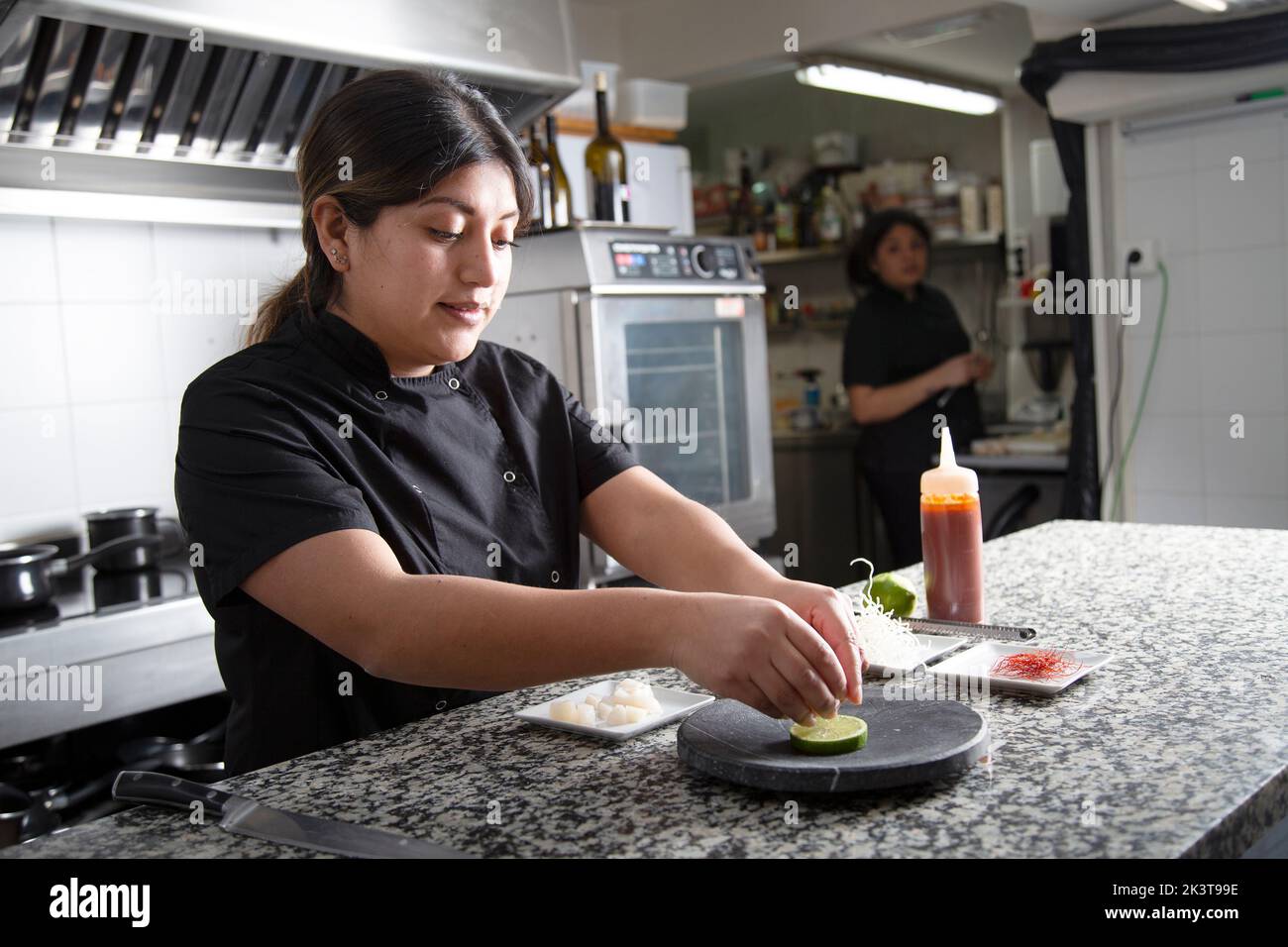 Hispanic female chef putting white daikon on lime slice placed on ...