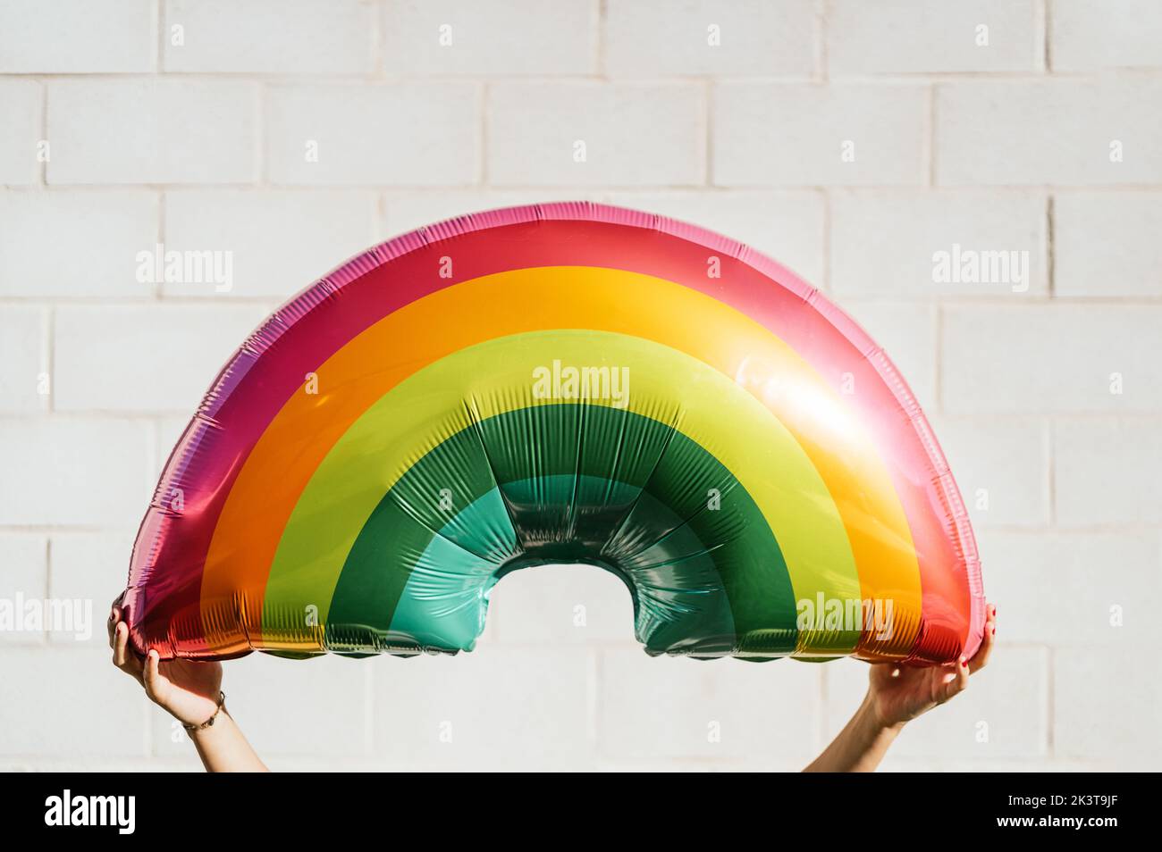 Crop anonymous person holding bright multicolored inflatable rainbow ...