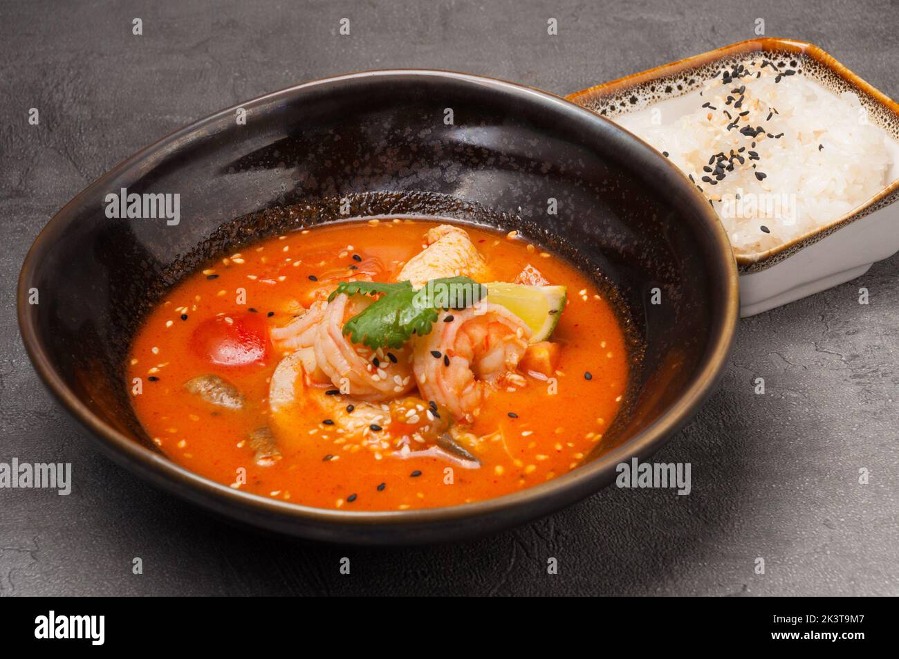 tasty tom yam with seafood in a dark dish and rice Stock Photo - Alamy