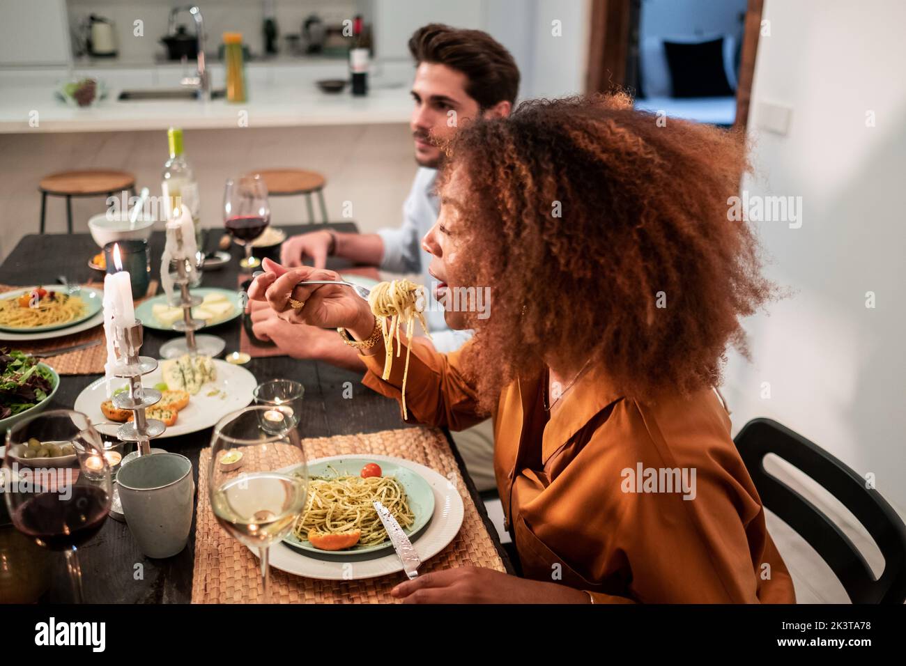 Side view of young African American female eating spaghetti while ...