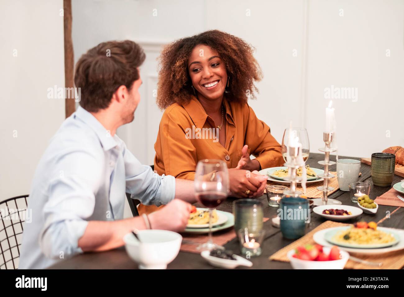 Cheerful romantic multiracial couple flirting while sitting at table ...