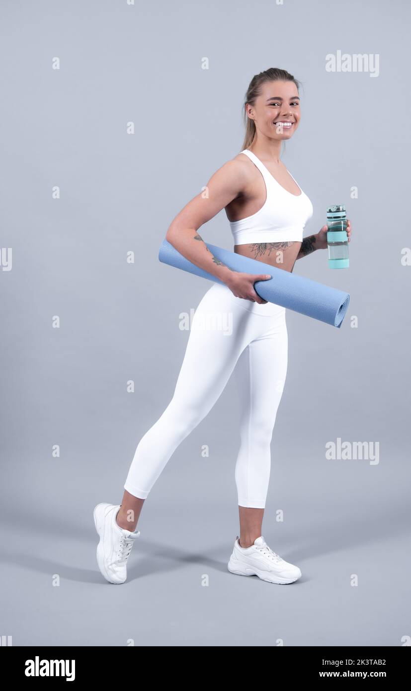 Sporty woman with yoga mat. Young fitness woman runner stretching legs ...