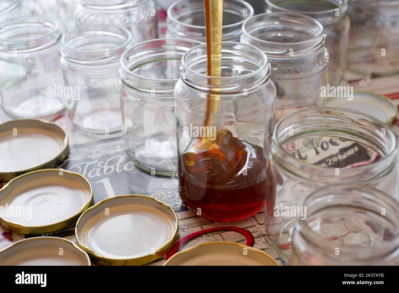 Filling of glass jars of honey on a table Stock Photo - Alamy