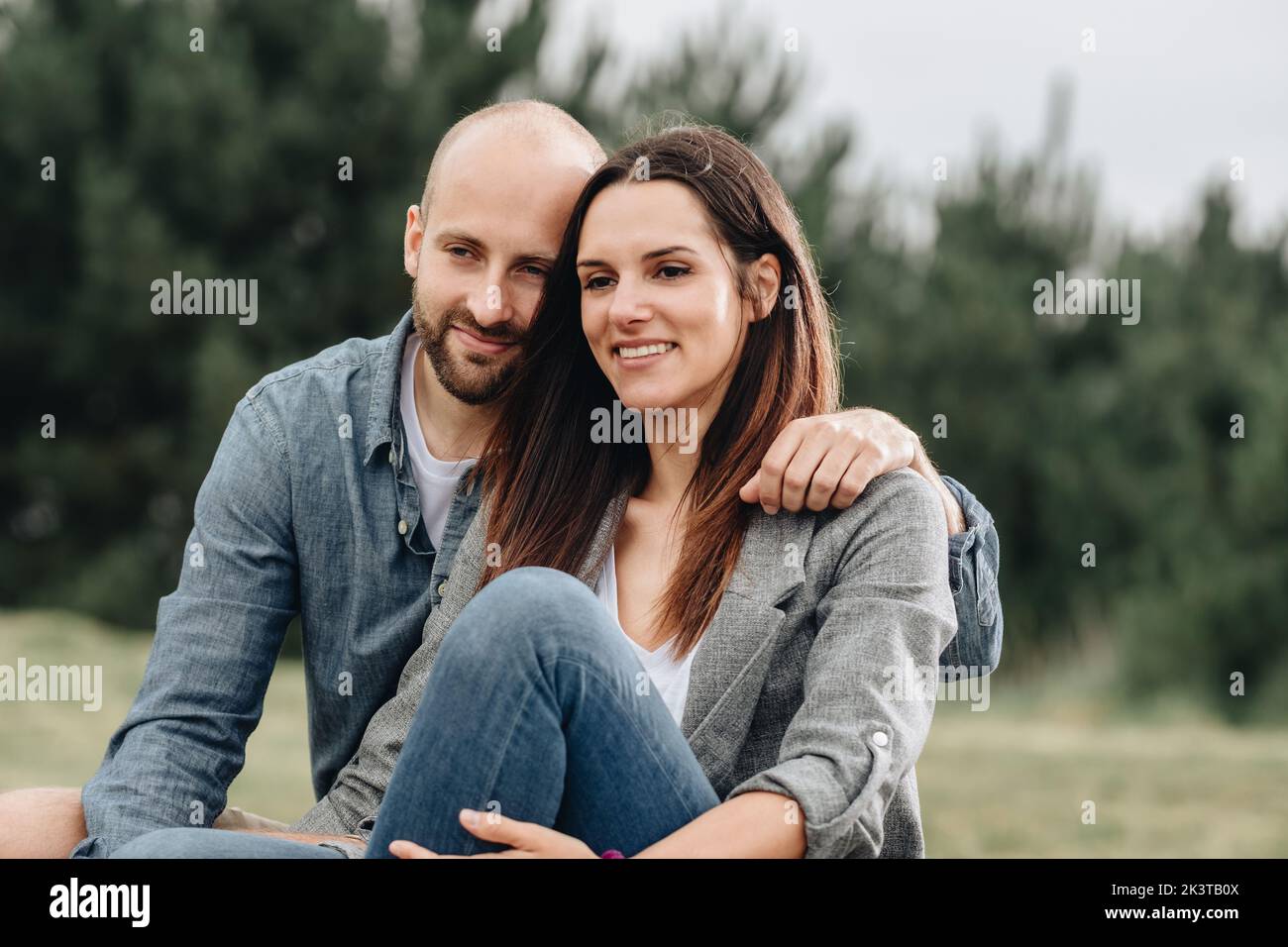 Cheerful smiling young amorous man and woman hugging and looking away ...