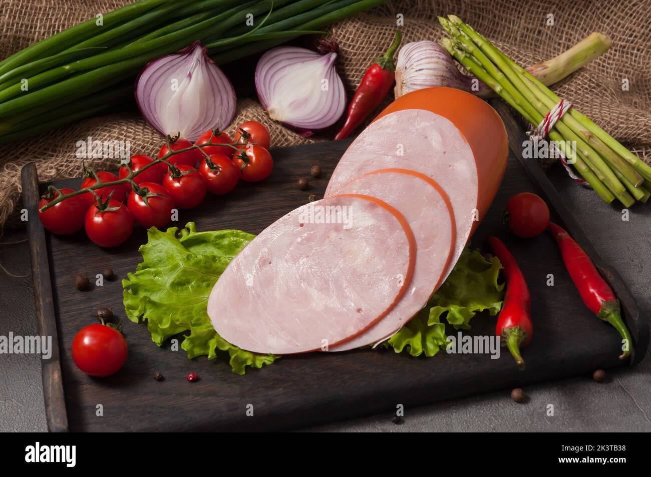 tasty chicken ham on a wooden board decorated with fresh vegetables ...
